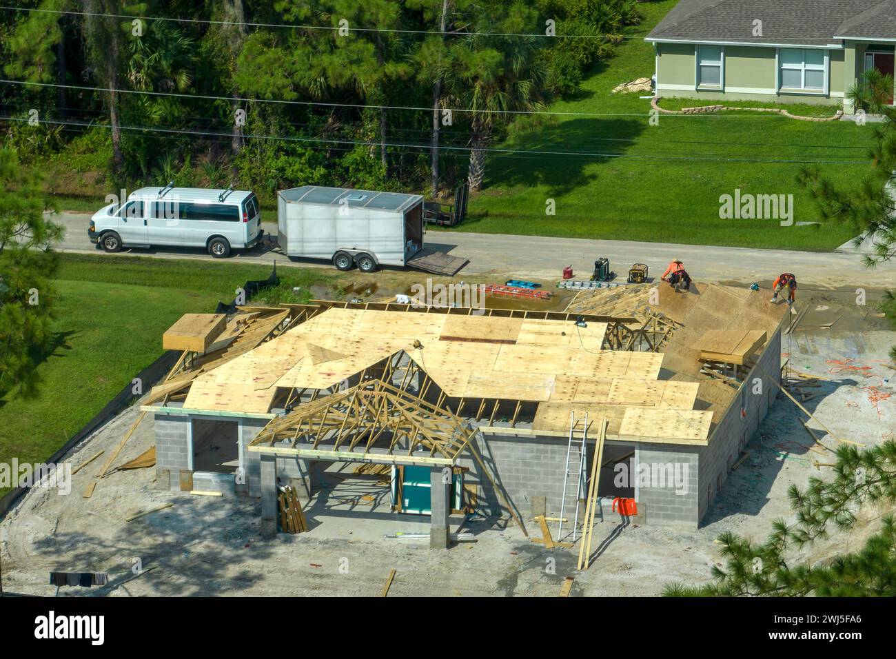 Builders working on roof construction of unfinished residential house ...