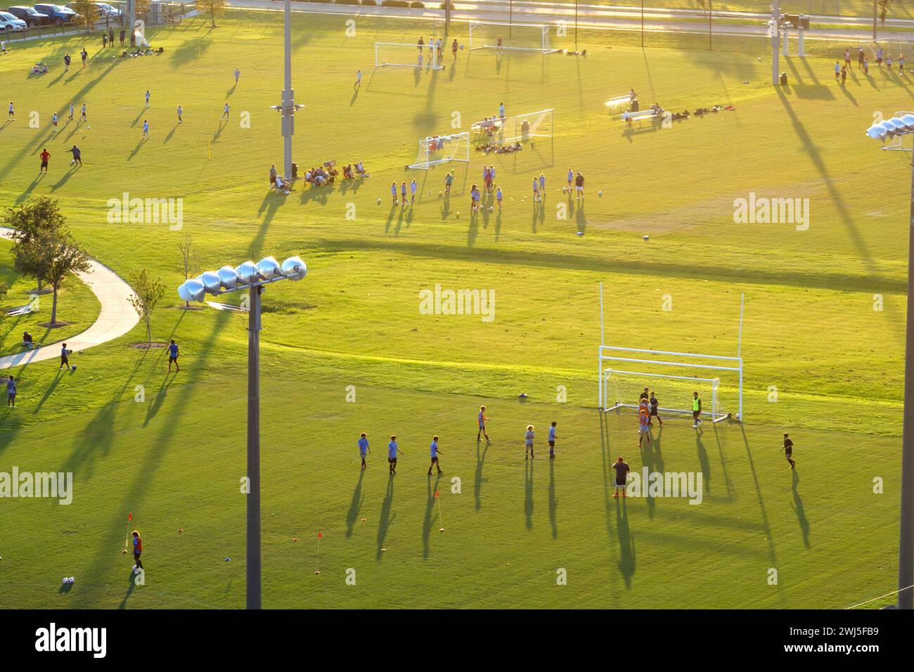 Public sports stadium with school kids playing football game at sunset ...