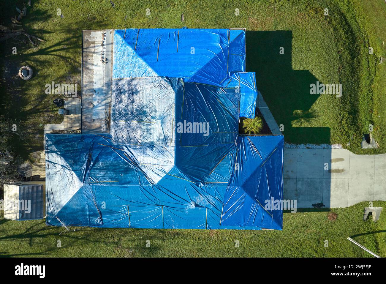 Aerial view of damaged in hurricane Ian house roof covered with blue ...
