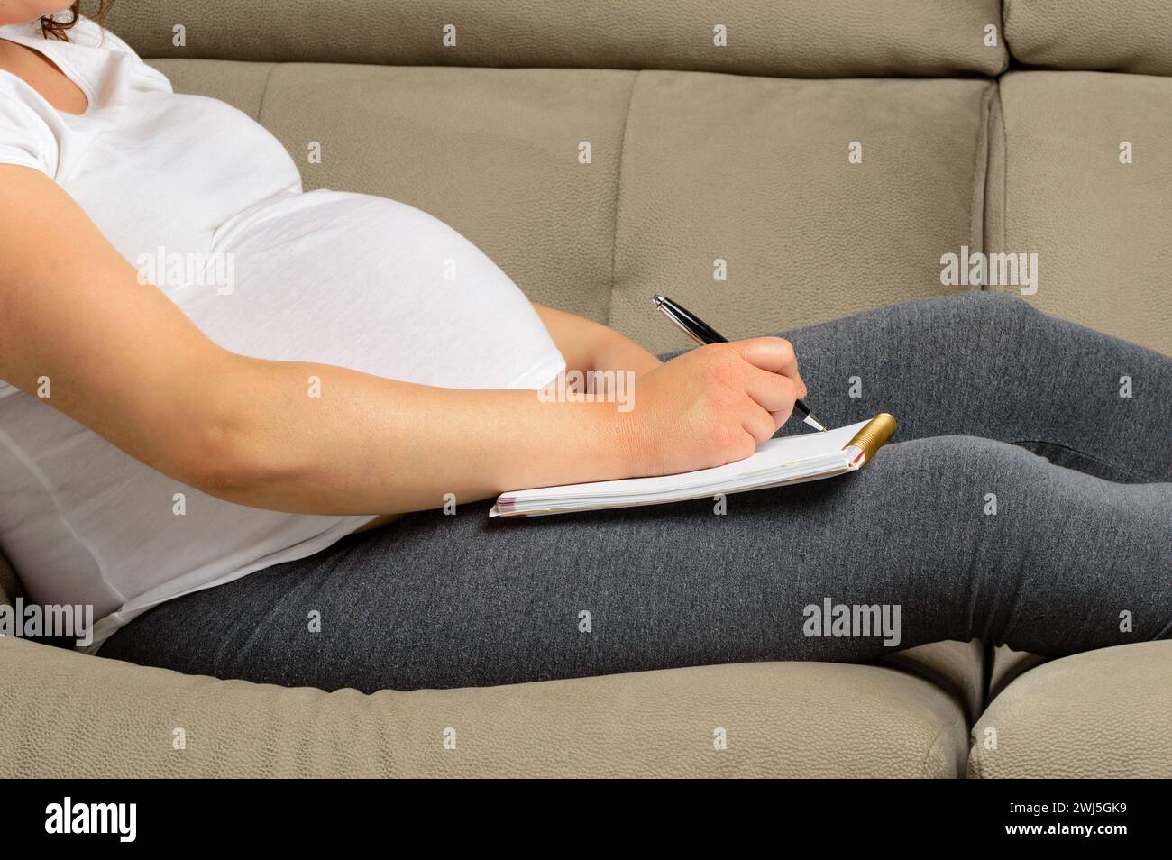Pregnant woman making packing list for maternity hospital at home Stock ...