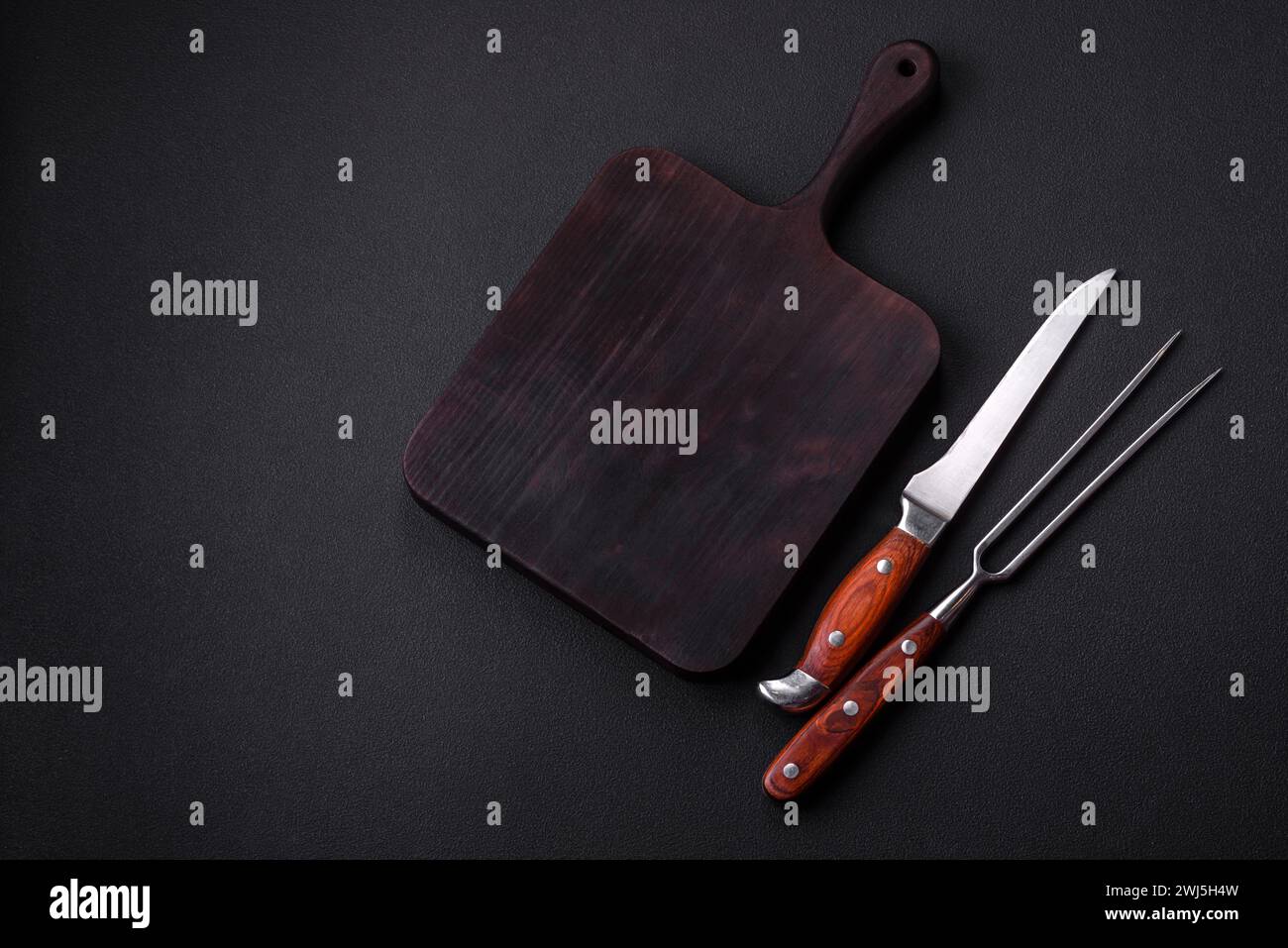Metal kitchen knife and fork on a dark textured concrete background ...
