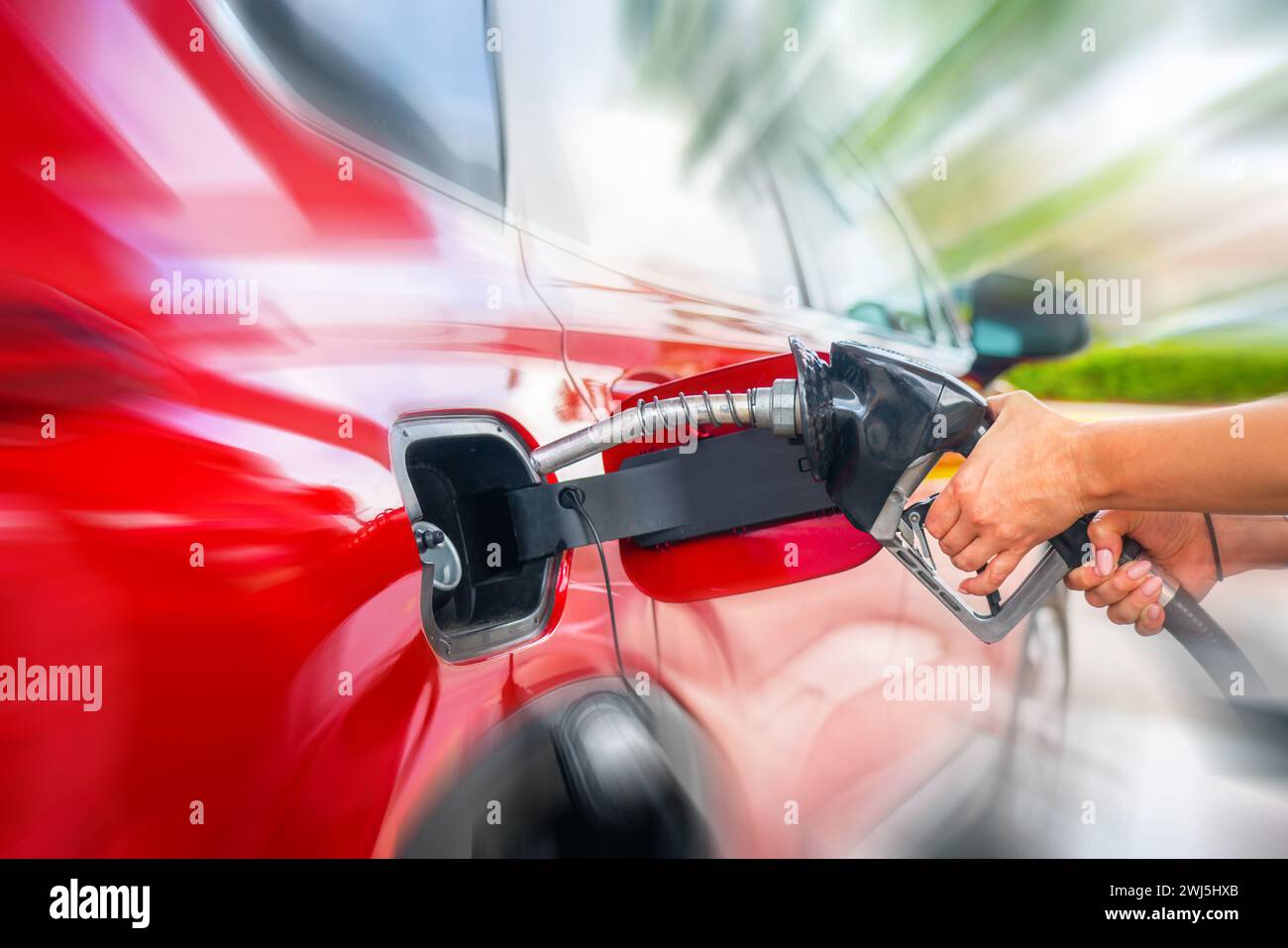 Female Hand with fuel pistol and red car with motion blur effect Stock ...
