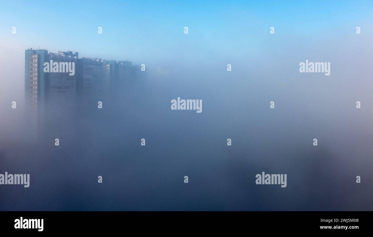 A white-and-blue multi-storey residential building is shrouded in fog ...