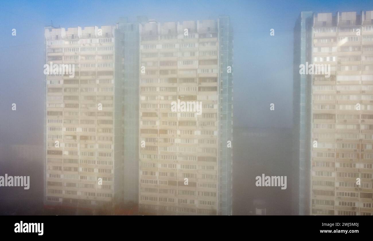 A white-and-blue multi-storey residential building is shrouded in fog ...