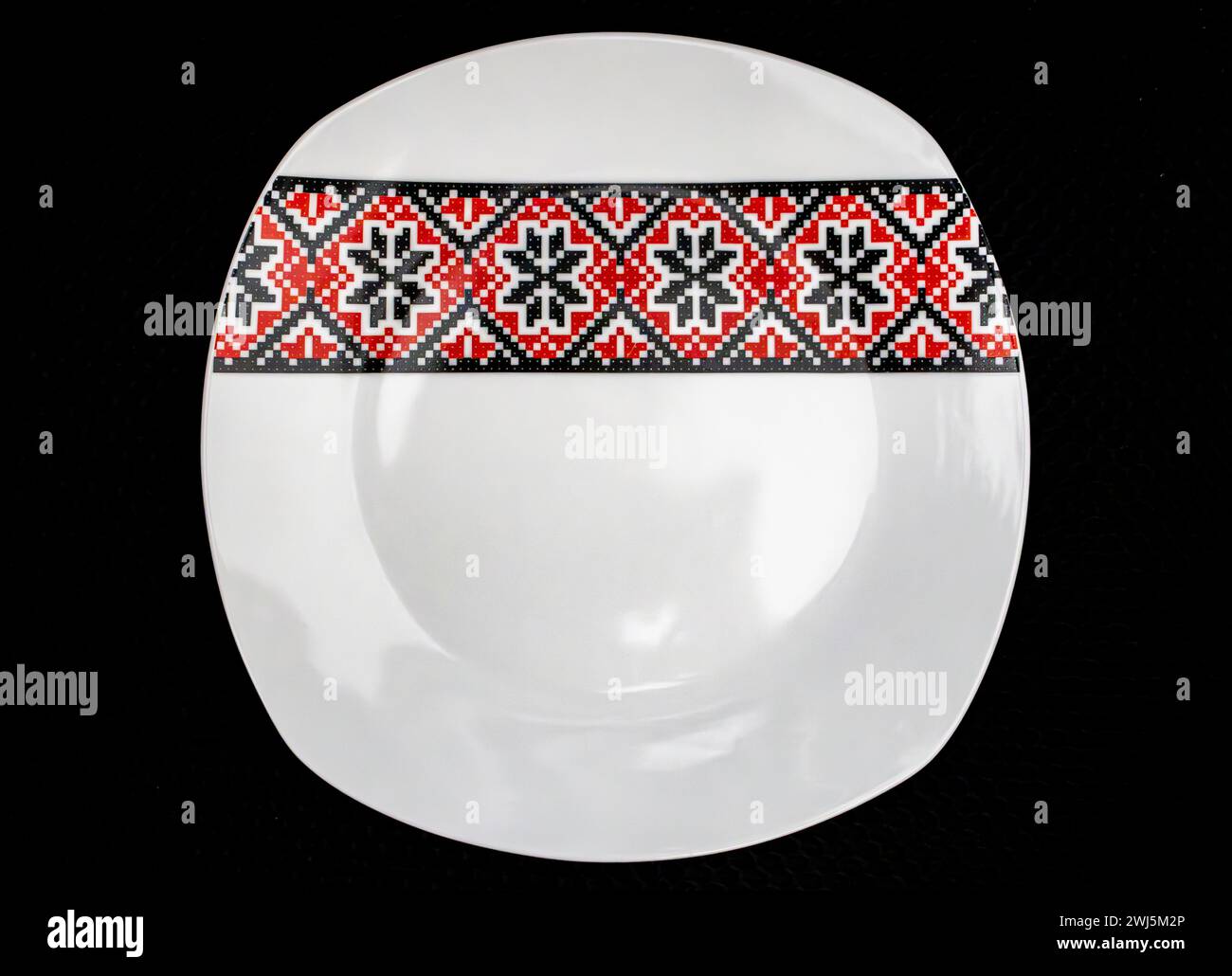 white plate with traditional Romanian motifs in red and black, on a ...