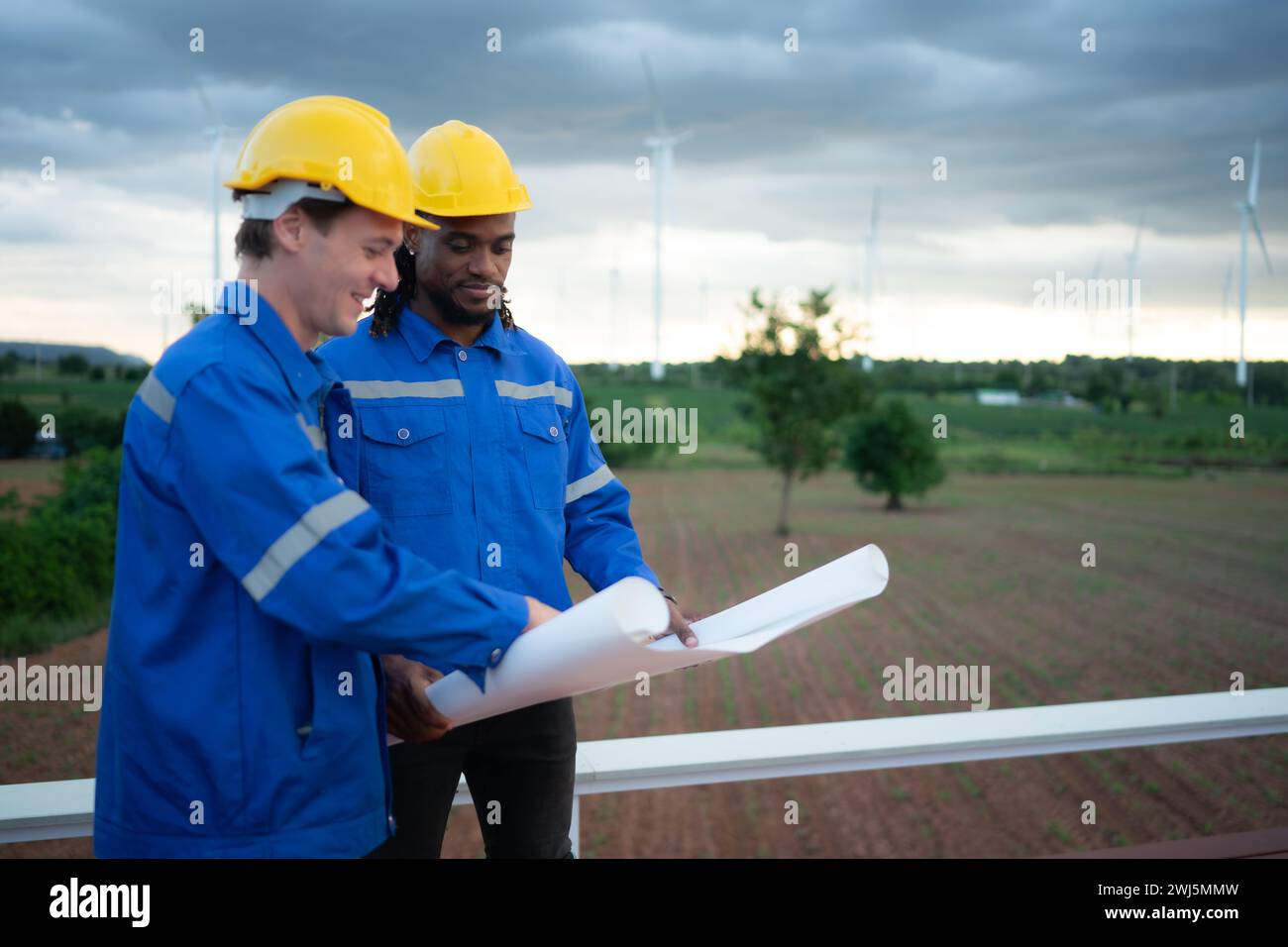 Back view of engineer and technician looking at wind turbines in the ...