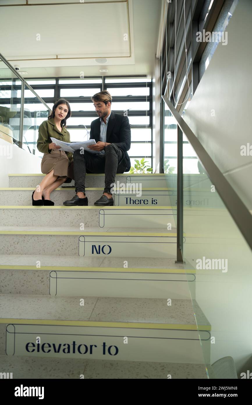 Both of businessperson sitting on stairs in office talk and exchange ...