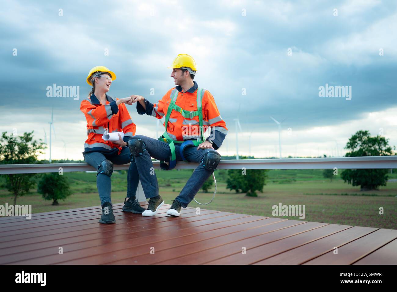 Two engineers discussing a project of wind turbine, They are sitting on ...