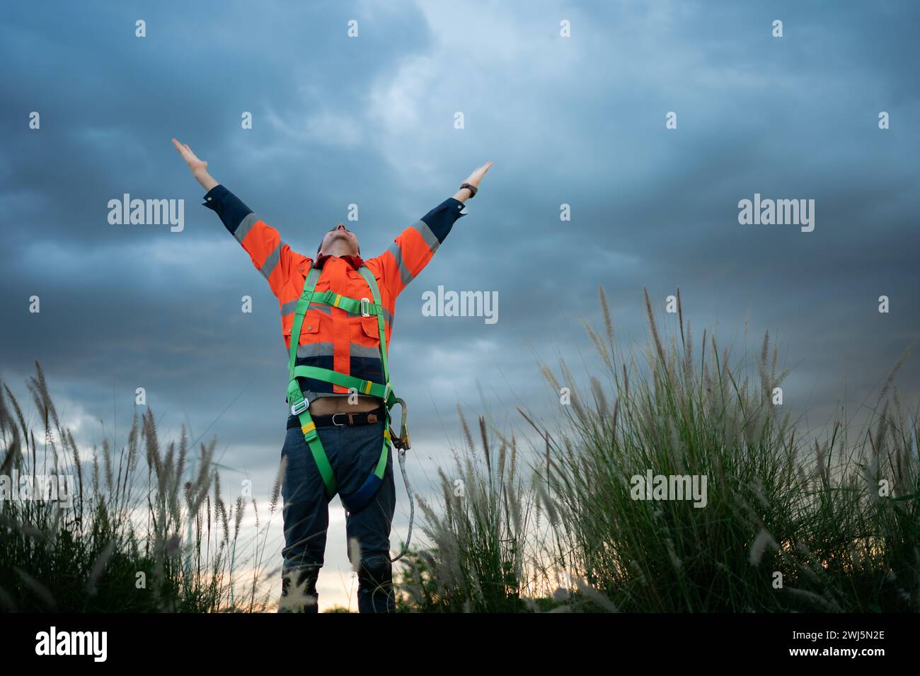 Young engineer working in a wind turbine field wear a safety vest raise ...