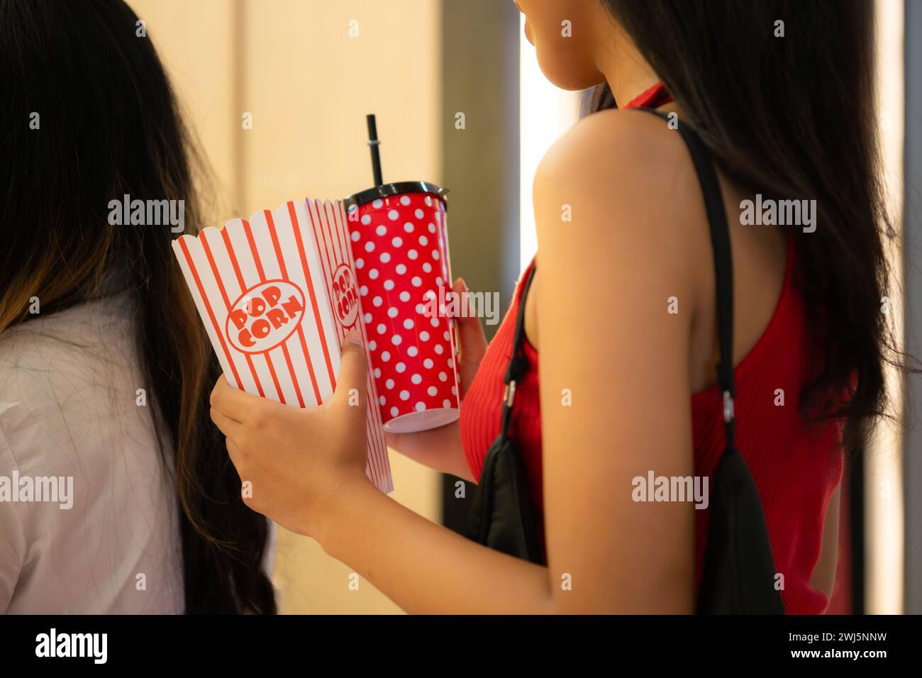 Young asian woman standing in line to buy movie tickets and in hand popcorn and drink Stock ...