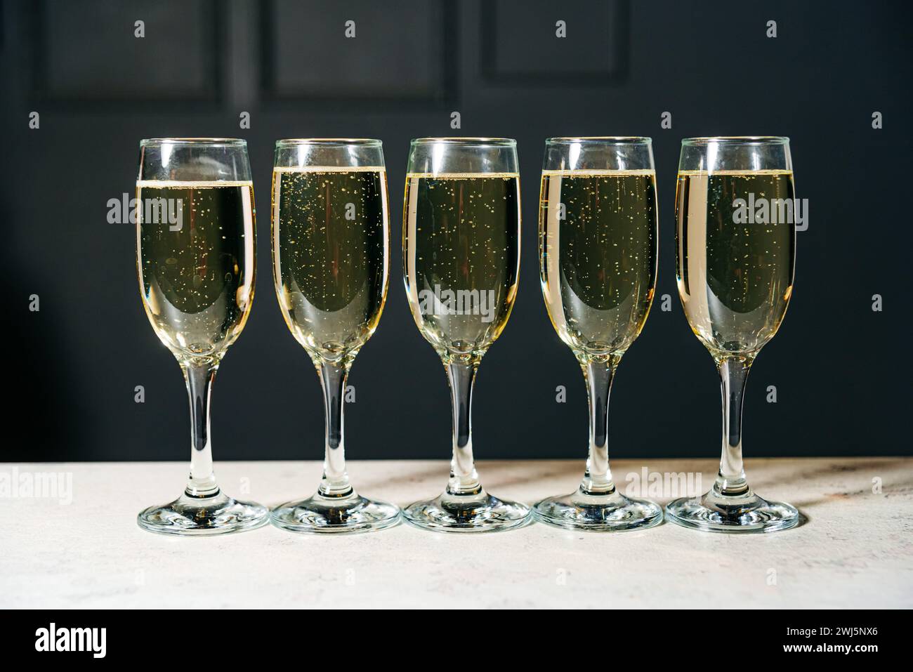 Five sparkling champagne glasses lined up on a table, with bubbles ...