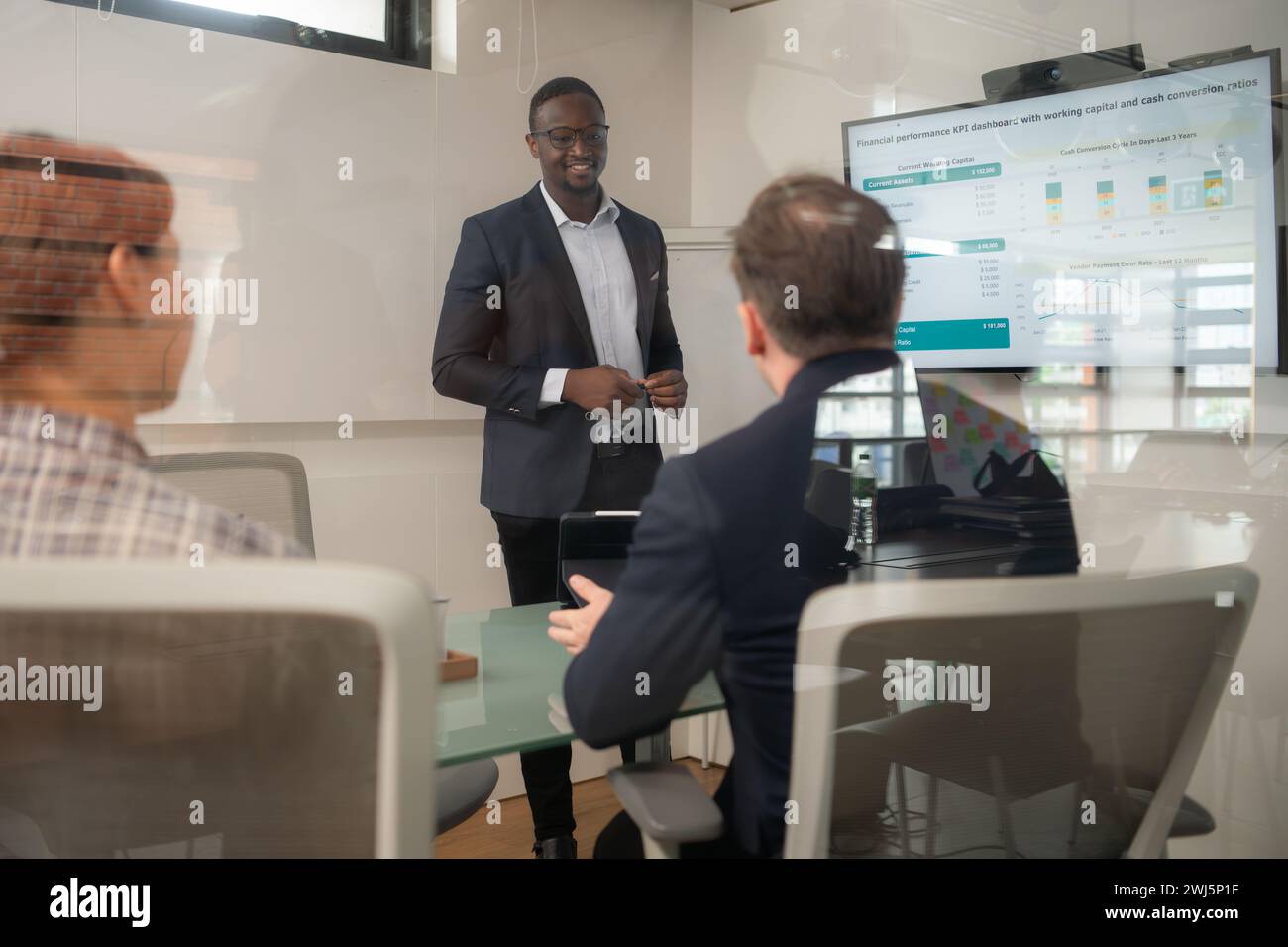 Rear view of two businesspeople having meeting around table in office ...