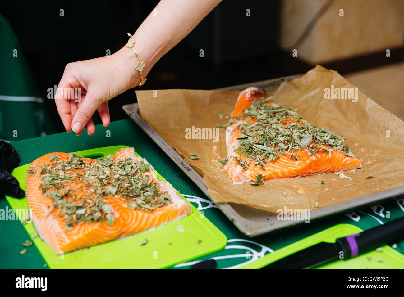 Fresh salmon fillet being seasoned with dried herbs on baking paper ...