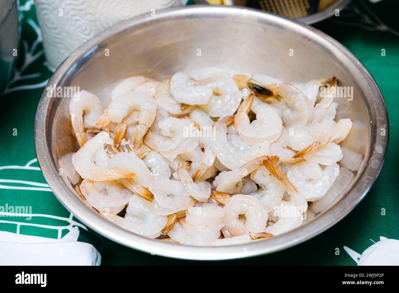 A bowl of fresh, uncooked shrimp with tails, prepared for culinary use ...