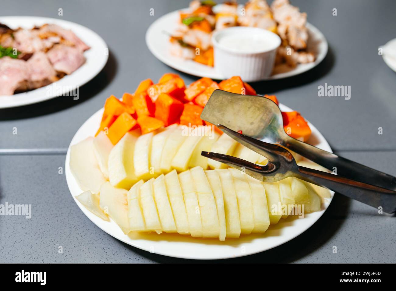 Sliced ripe melon and vibrant papaya presented on white platters, ready ...