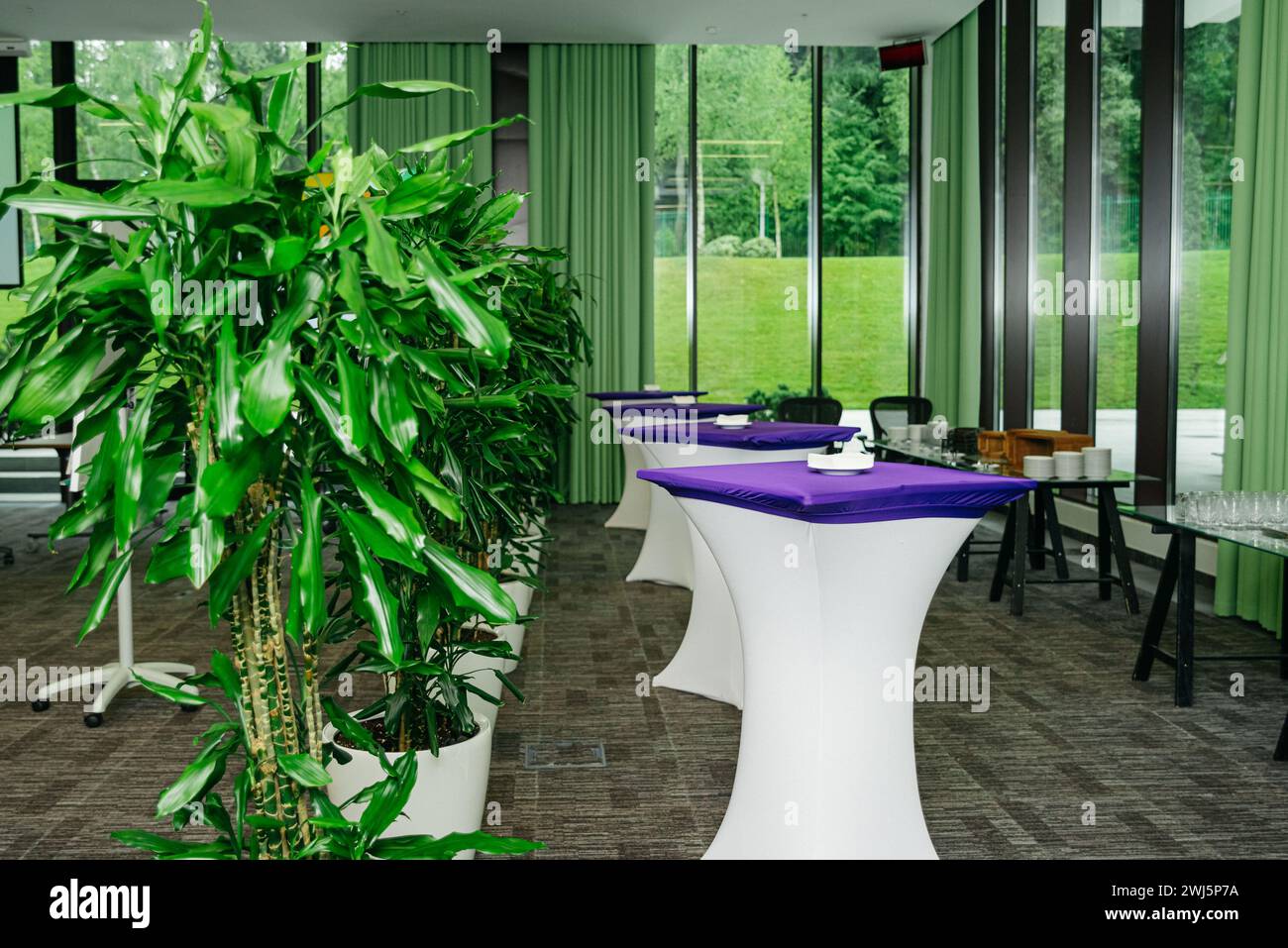 Contemporary event space with tall cocktail tables dressed in white and ...