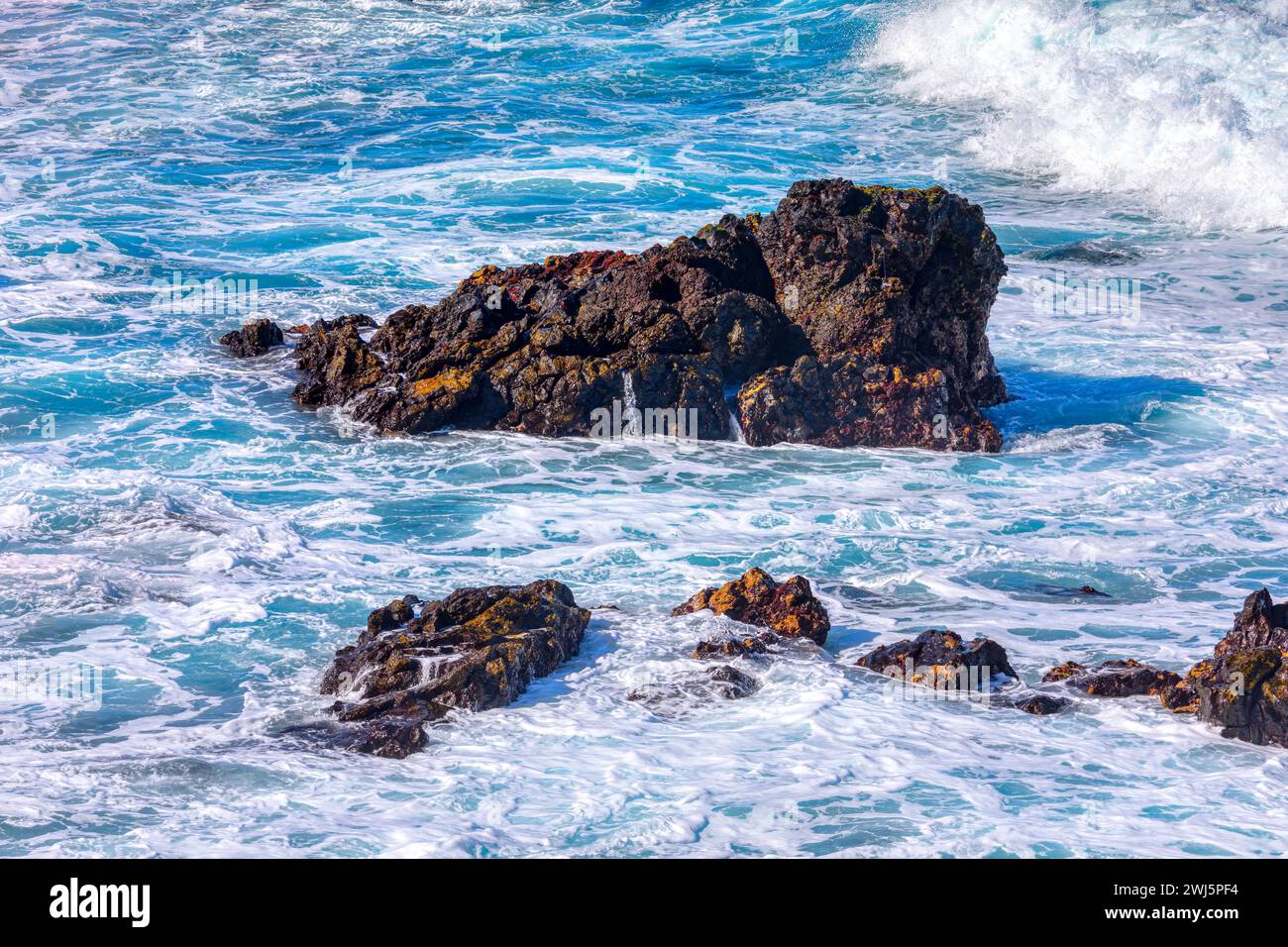 Massive rock stands in the midst of ocean waves, creating a captivating ...