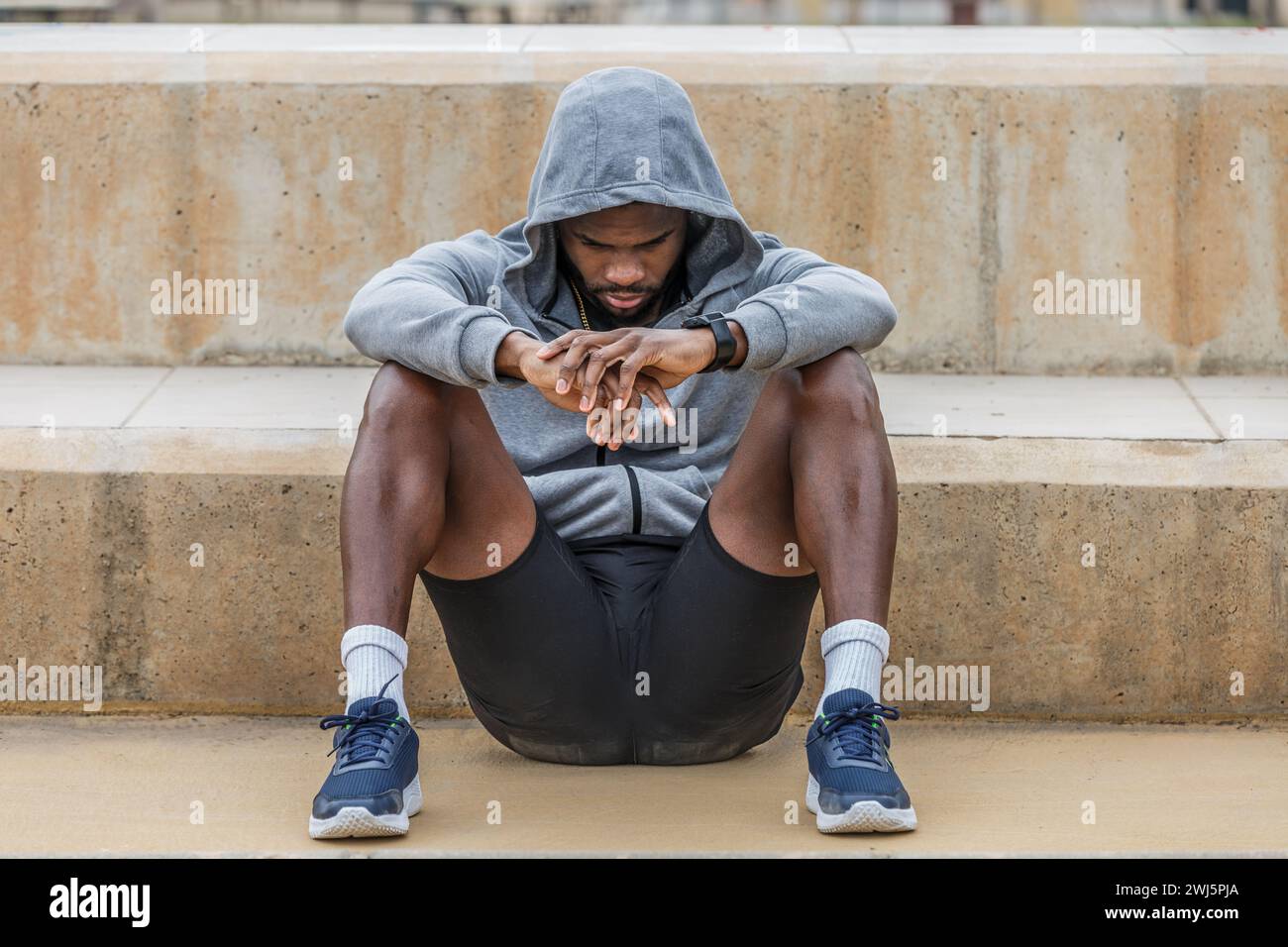 Full body of young upset African American male athlete sitting with ...