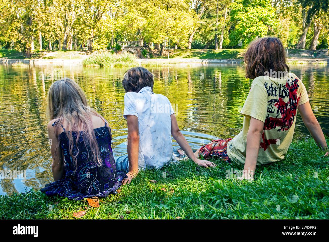 children schoolchildren sitting with their backs near the lake Stock ...