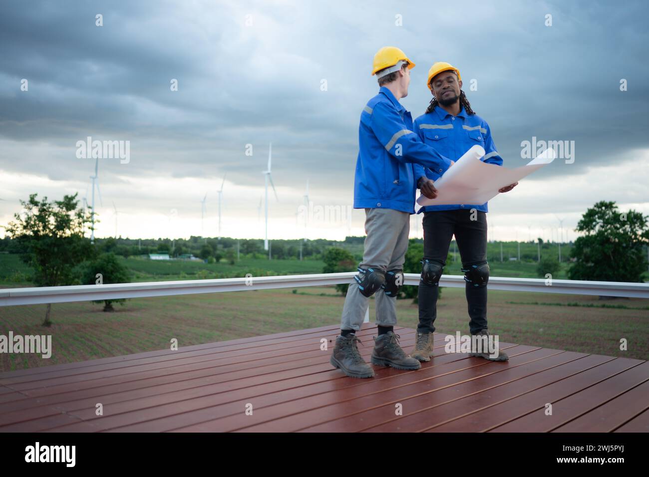 Back view of engineer and technician looking at wind turbines in the ...