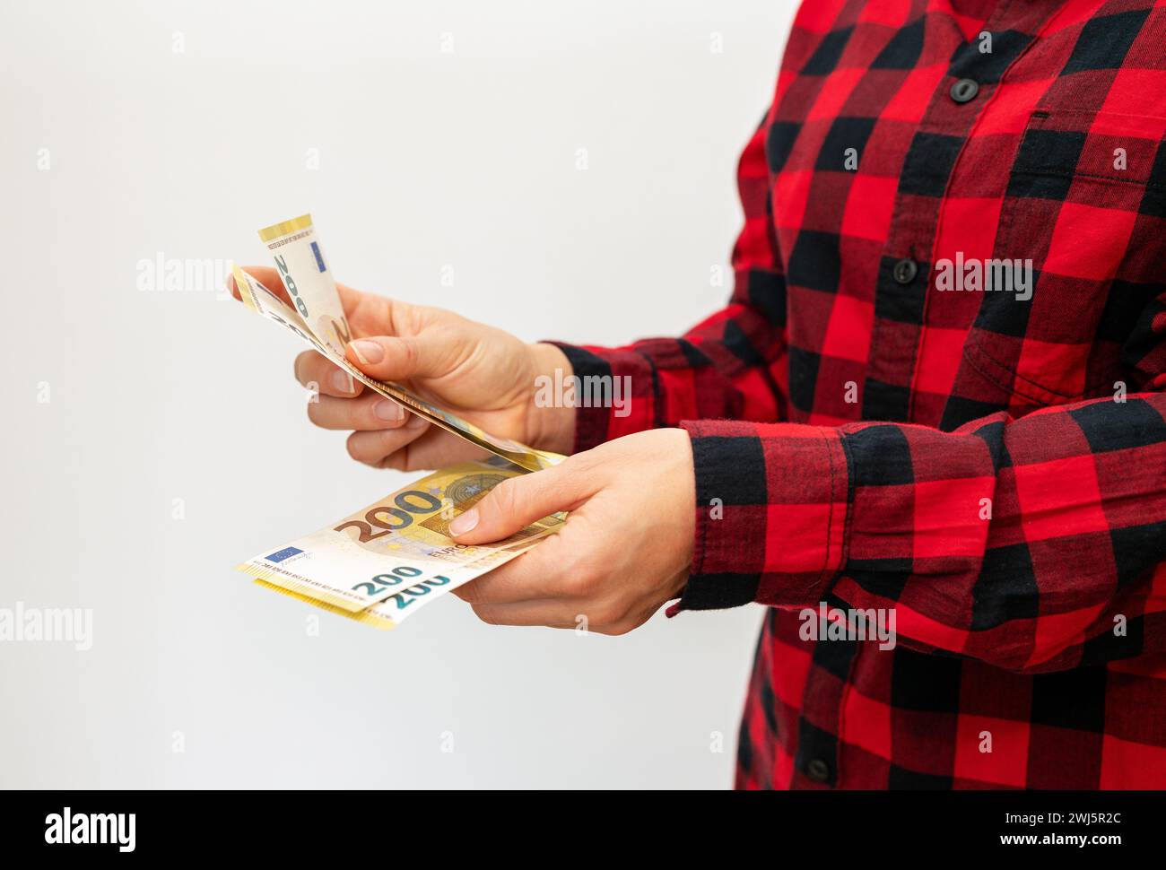 Female person in red shirt counting euro banknotes in hands. 200 euros ...