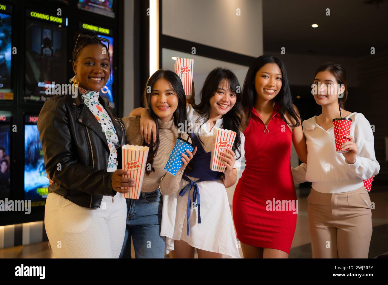Group of happy friends watching movie in cinema and eating popcorn at ...