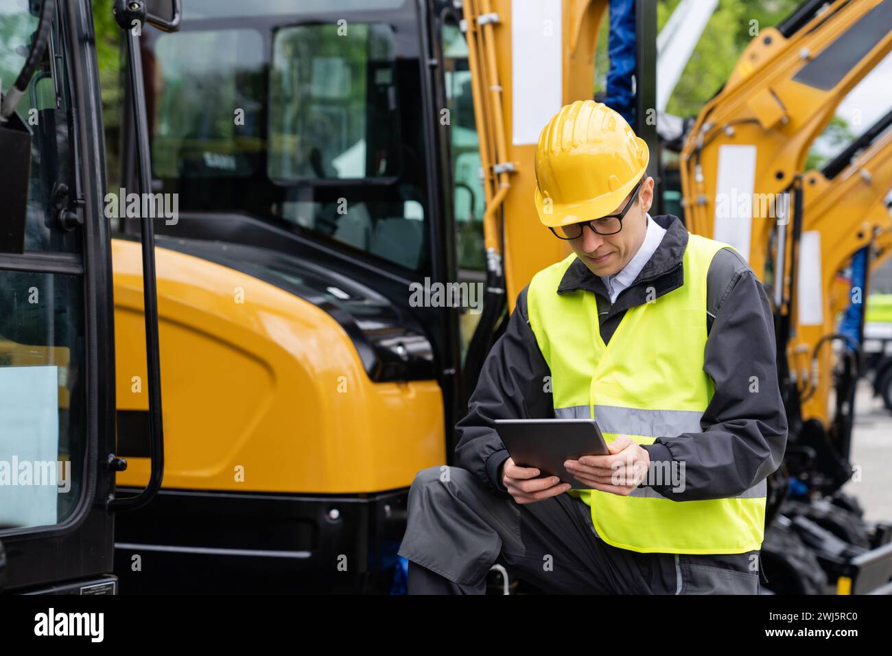 Engineer in a helmet with a digital tablet stands next to construction ...