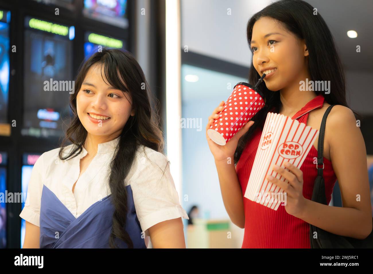 Young asian woman standing in line to buy movie tickets and in hand popcorn and drink Stock ...
