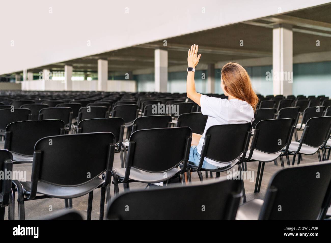 Only one attendee at conference. One woman with raised arm sitting in ...