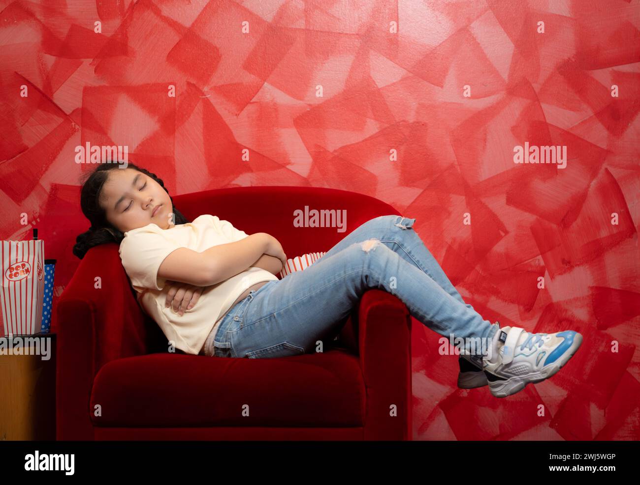 Girl rest and waiting for watching a movie on the red sofa in the front ...