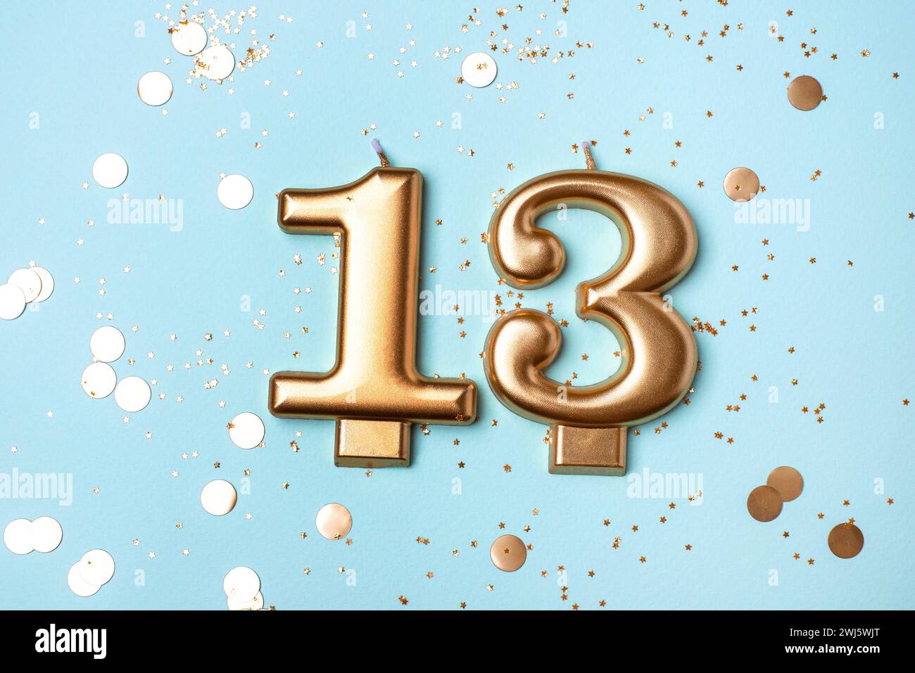 Gold candles in the form of number thirteen on blue background with ...