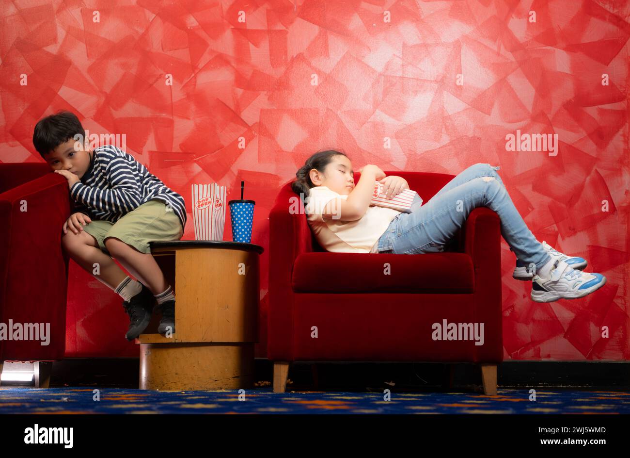 Boy and girl rest and waiting for watching a movie on the red sofa in ...
