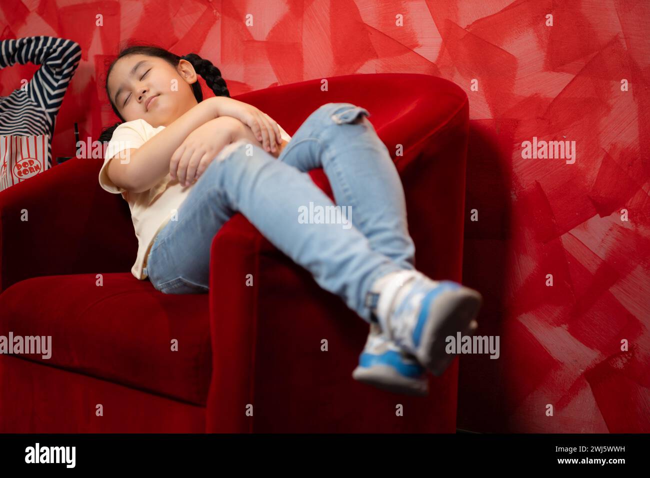 Girl rest and waiting for watching a movie on the red sofa in the front ...