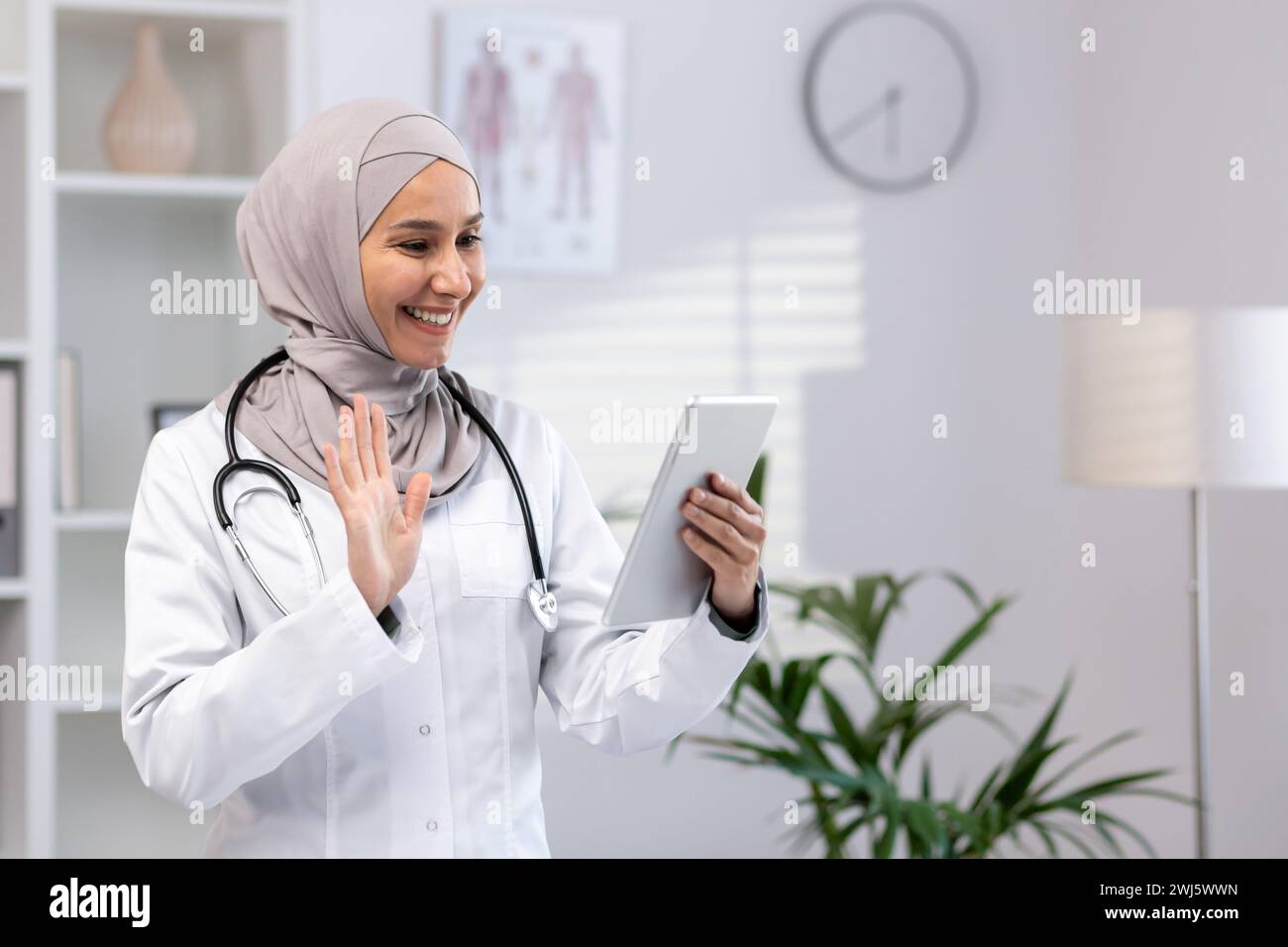A cheerful Muslim healthcare professional in a hijab engages with ...