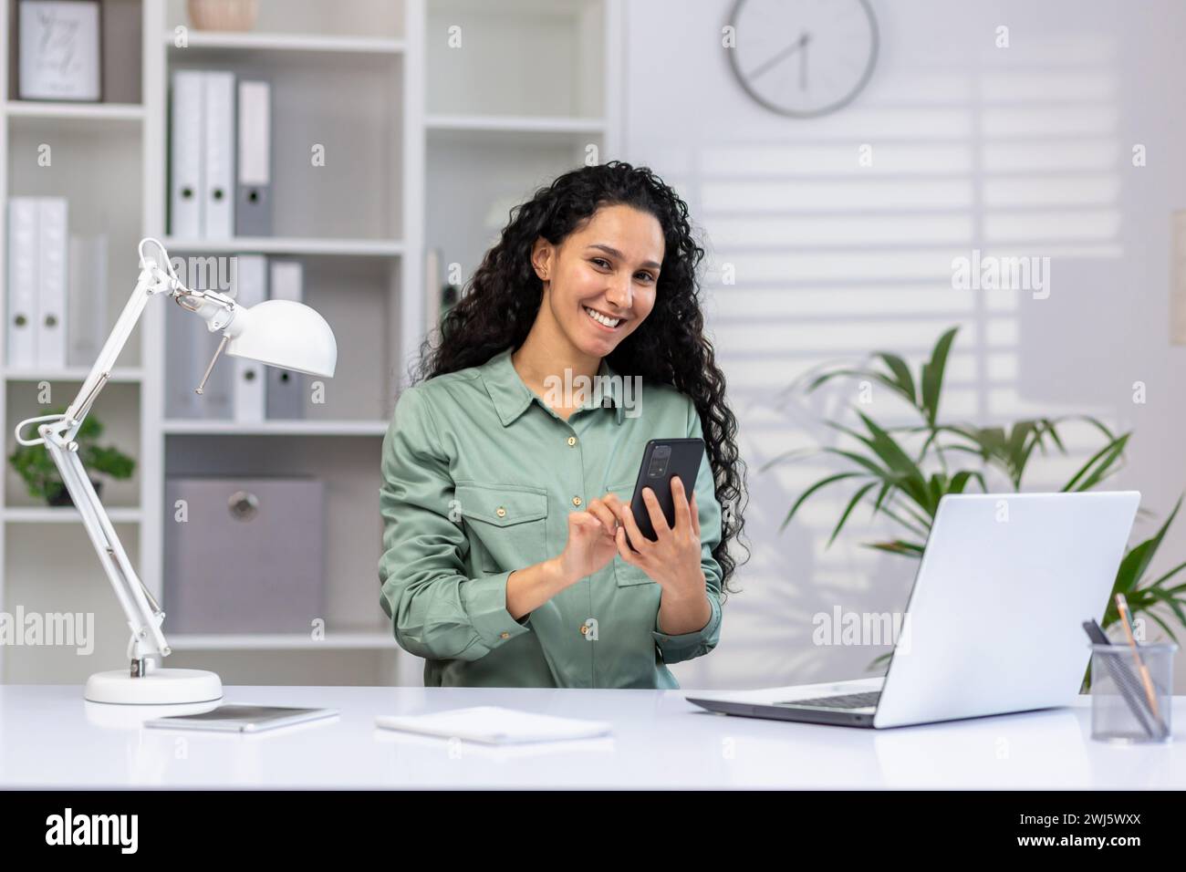 Professional hispanic woman working in a bright office space with a ...