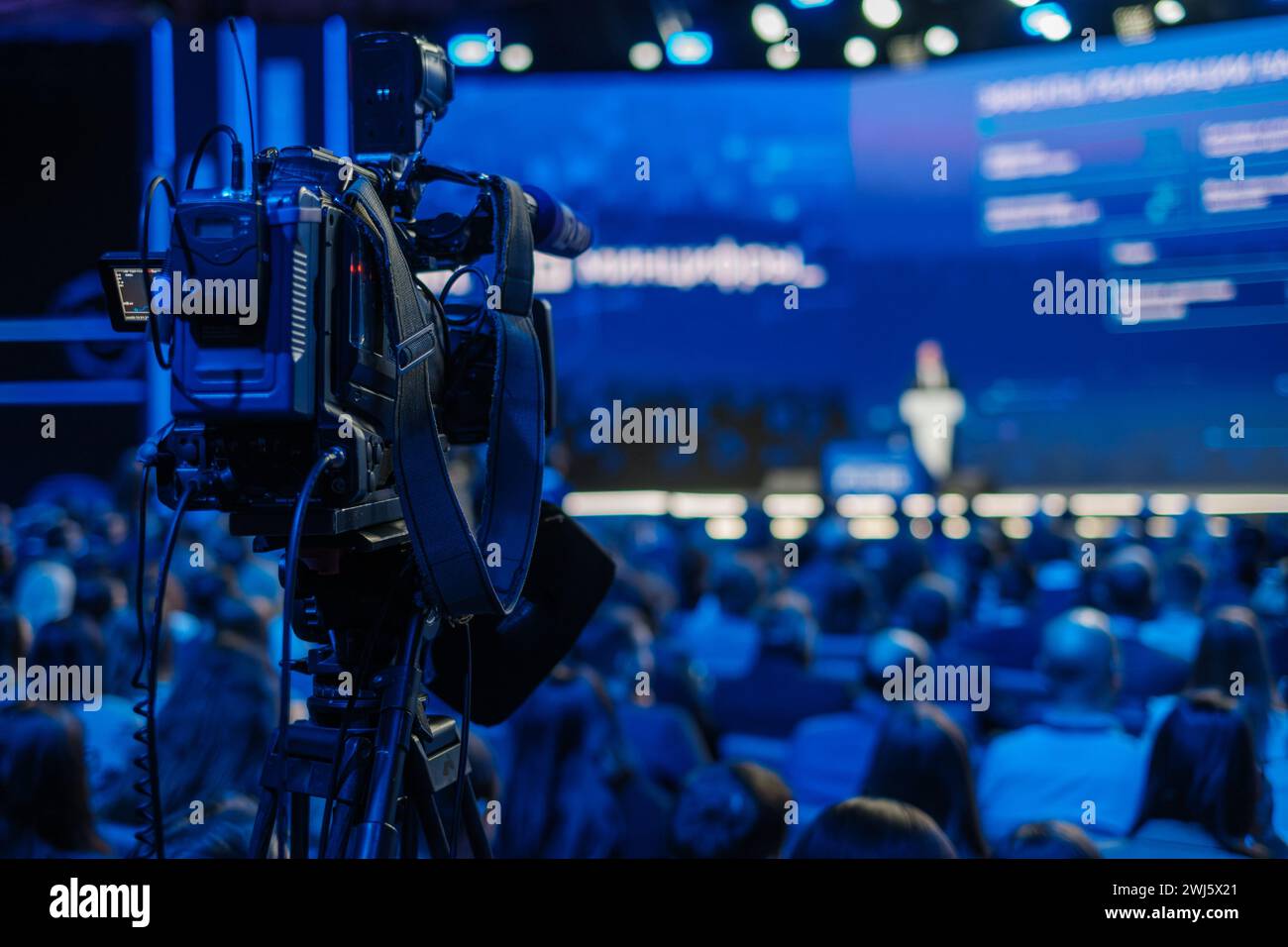 Back view of a professional video camera recording a speaker at a ...