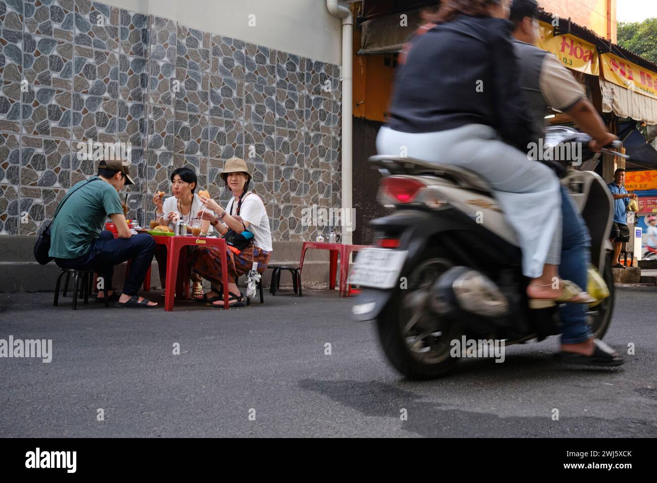 Jan 2024, People sitting down on small plastic stools on a street side ...