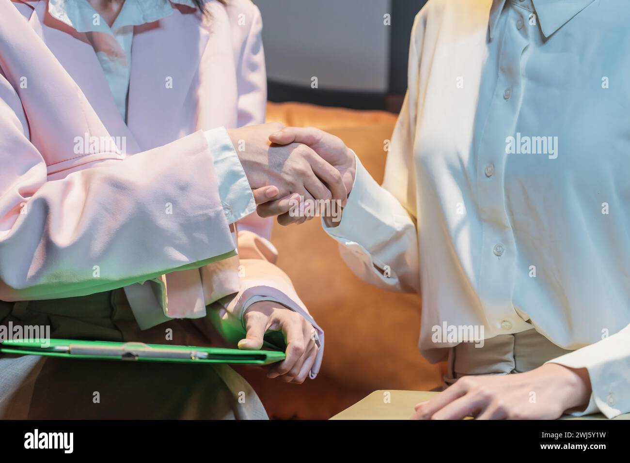 The two professional women in formal clothing sealing a deal with a ...
