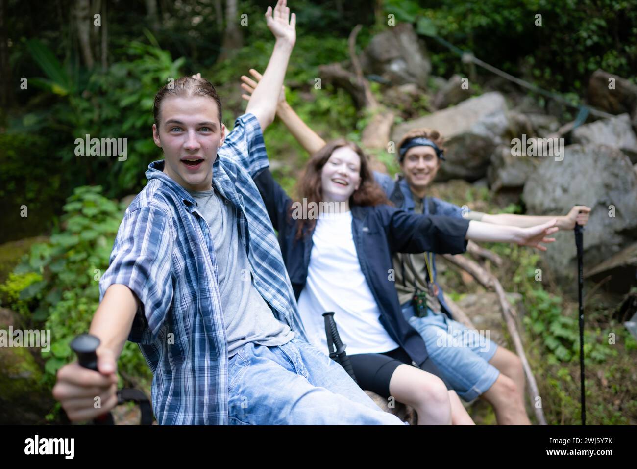 Group of friends with backpacks and sticks sitting on a fallen tree ...