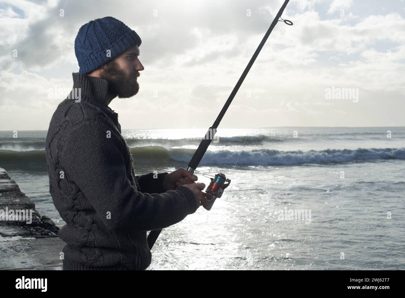 Night, fishing and man at a beach with pole for water hobby, recreation ...