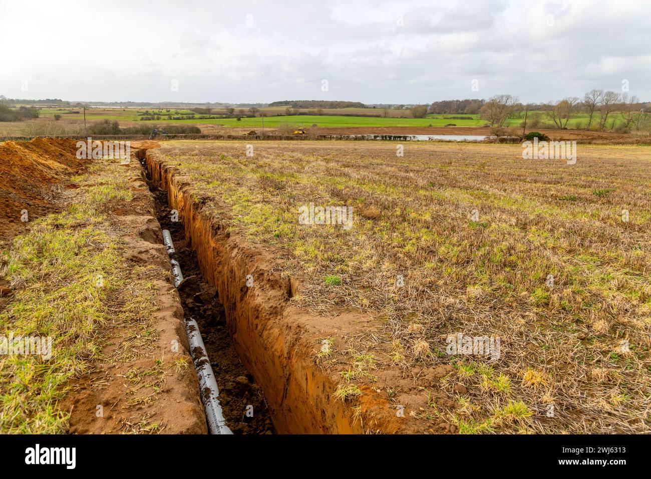 Farm irrigation water supply pipeline excavated in ditch in sandy soil ...