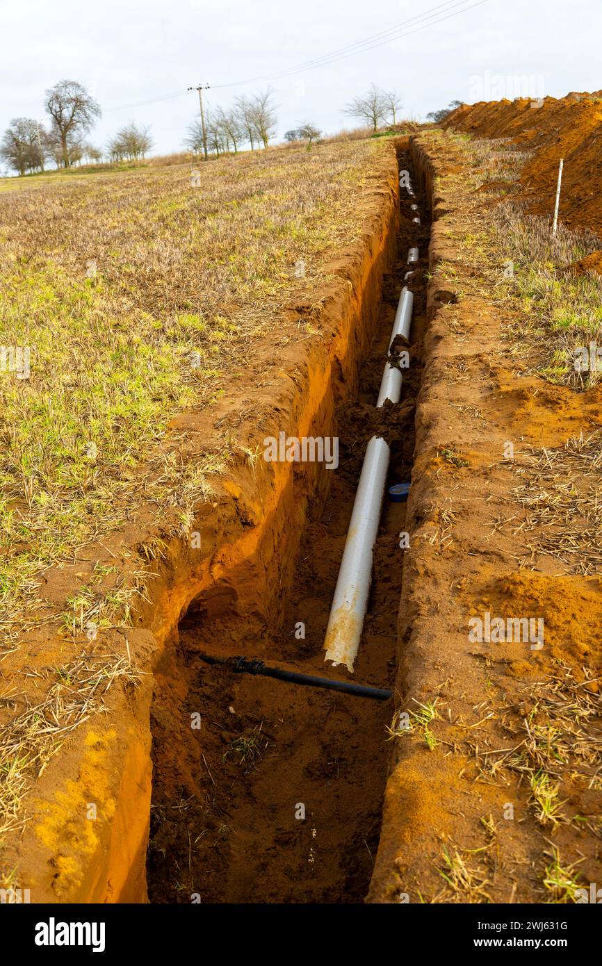 Farm irrigation water supply pipeline excavated in ditch in sandy soil ...