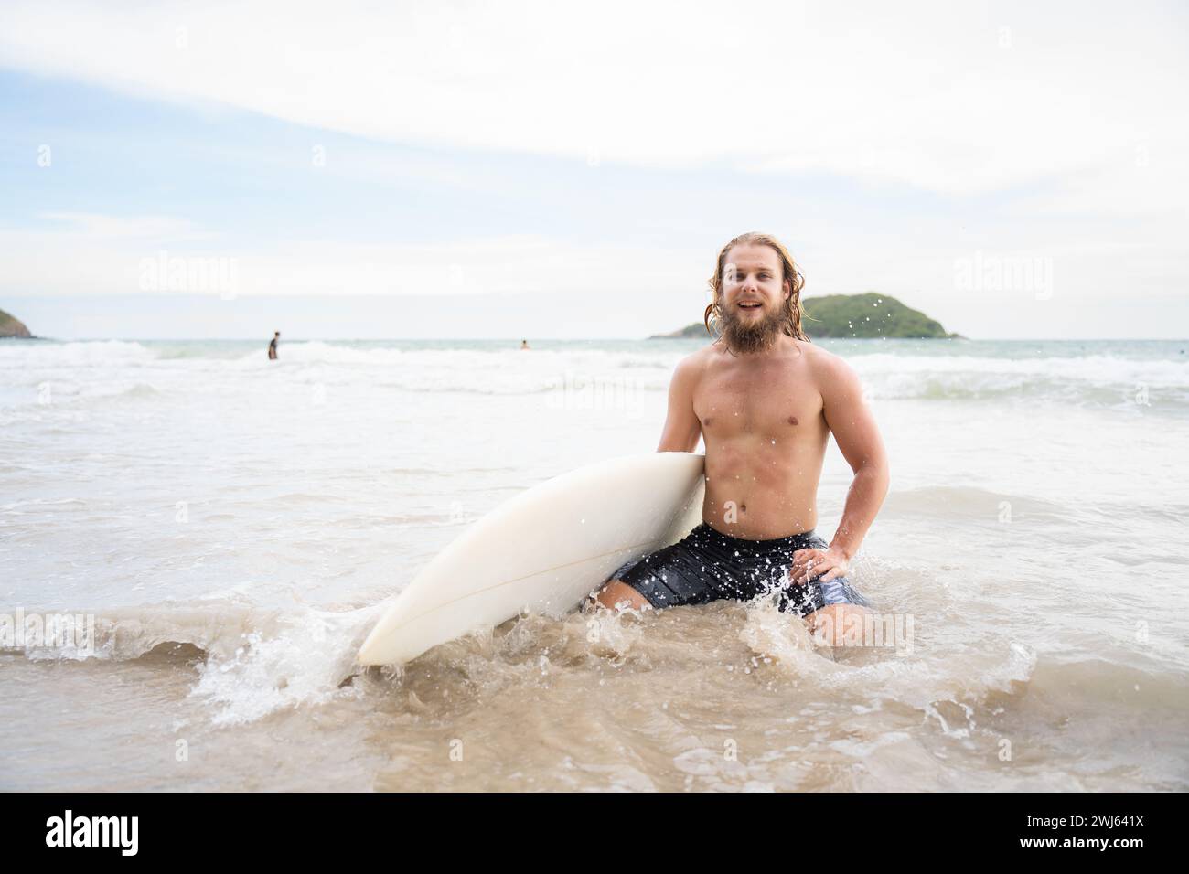 Young man surfing on the beach having fun and balancing on the ...