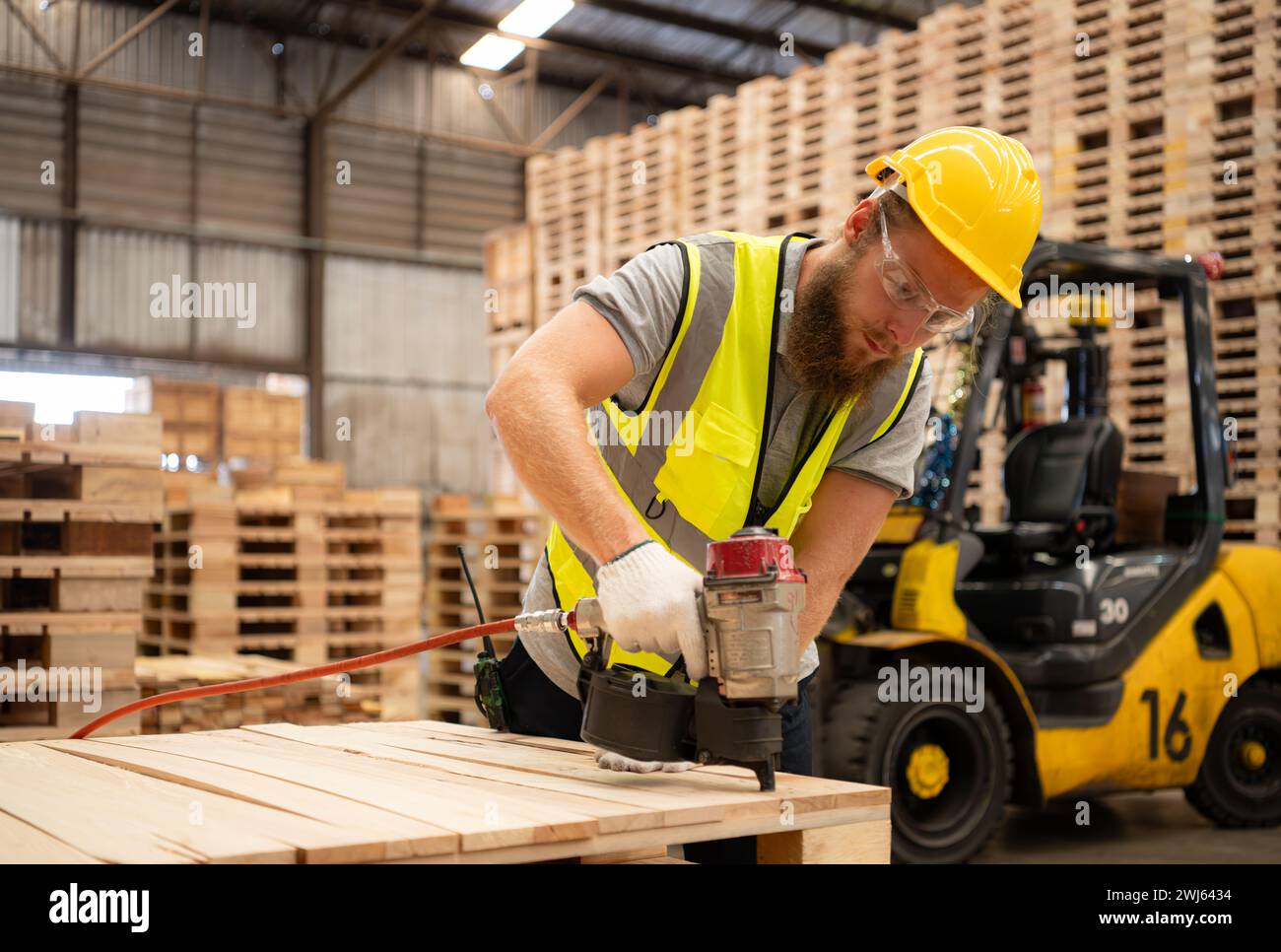Young workers working in a woodworking factory, Using a nailing machine ...