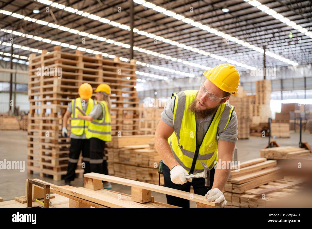 Young workers working in a woodworking factory, Using a hammer to work ...
