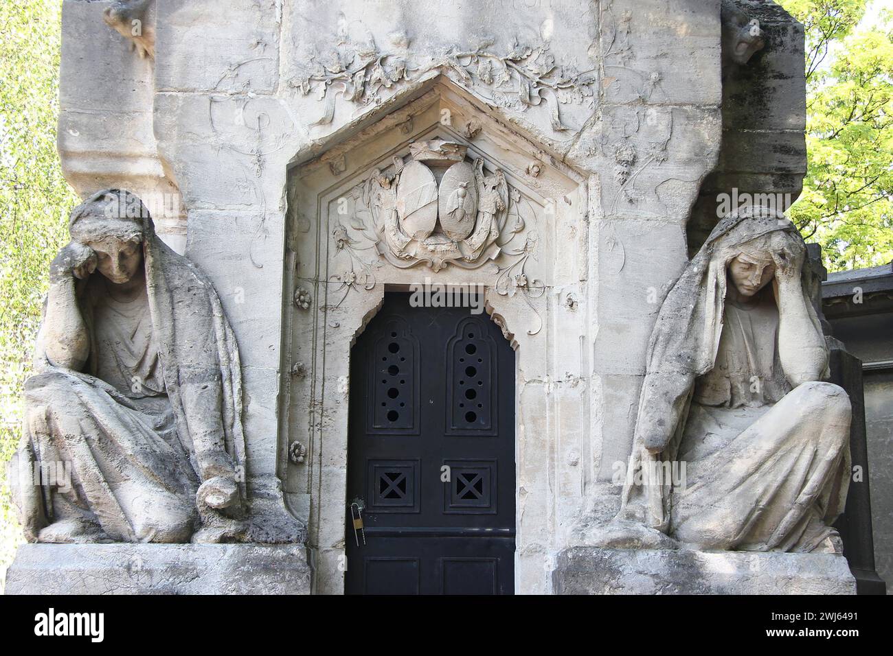 The two statues positioned before a doorway in a cemetery in Paris ...