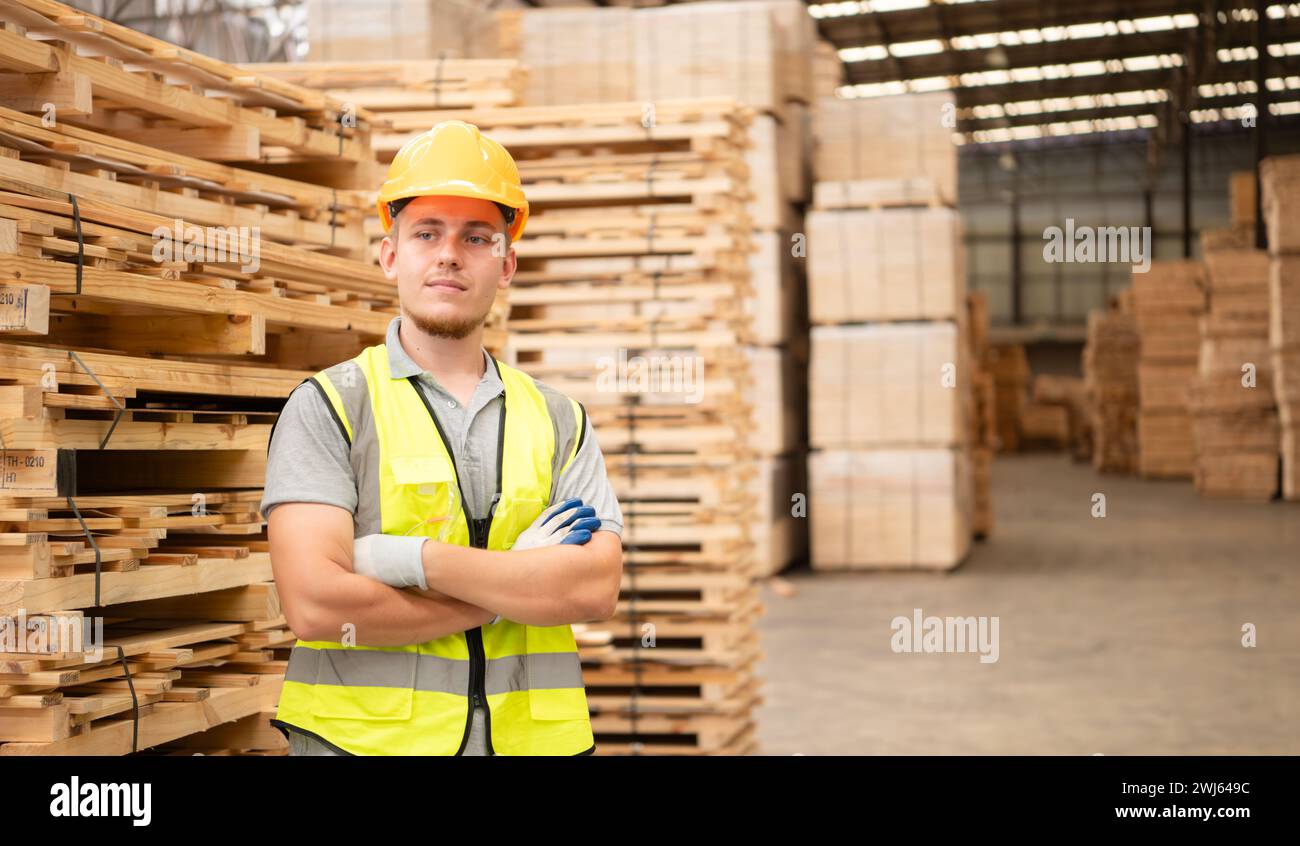 Portrait of warehouse worker checking stock of wooden pallets in ...