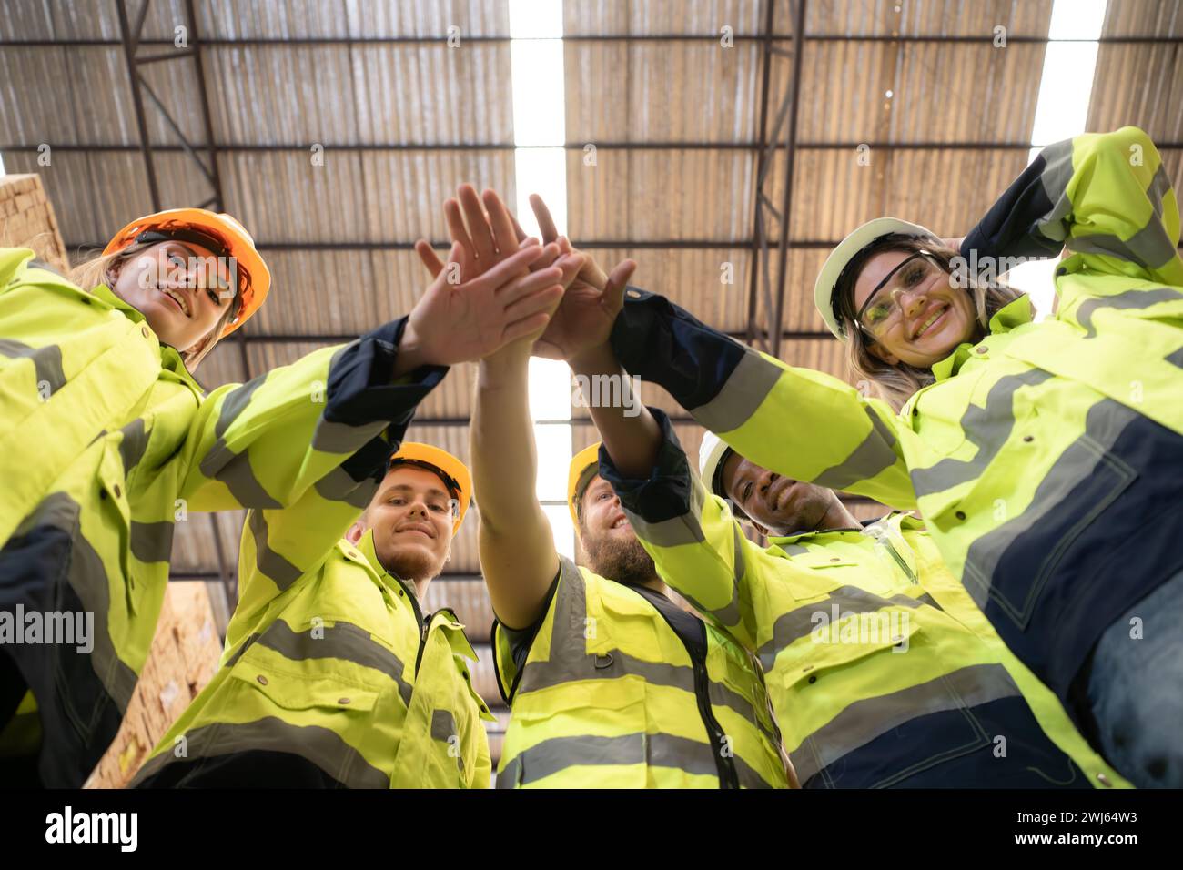 Portrait of happy workers giving high five at warehouse. This is a a ...