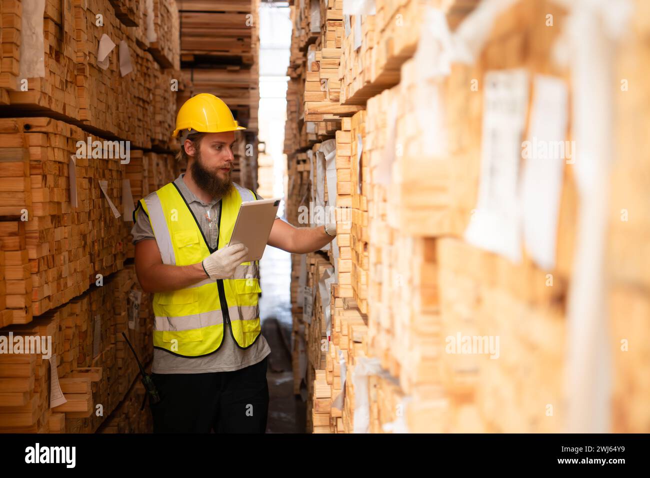 Portrait of warehouse worker checking stock of wooden pallets in ...