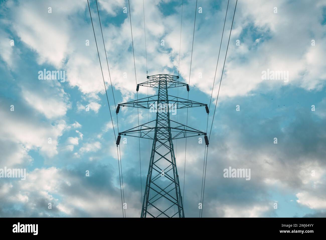 Electricity pylon with overhead powerline cables against cloudy sky ...